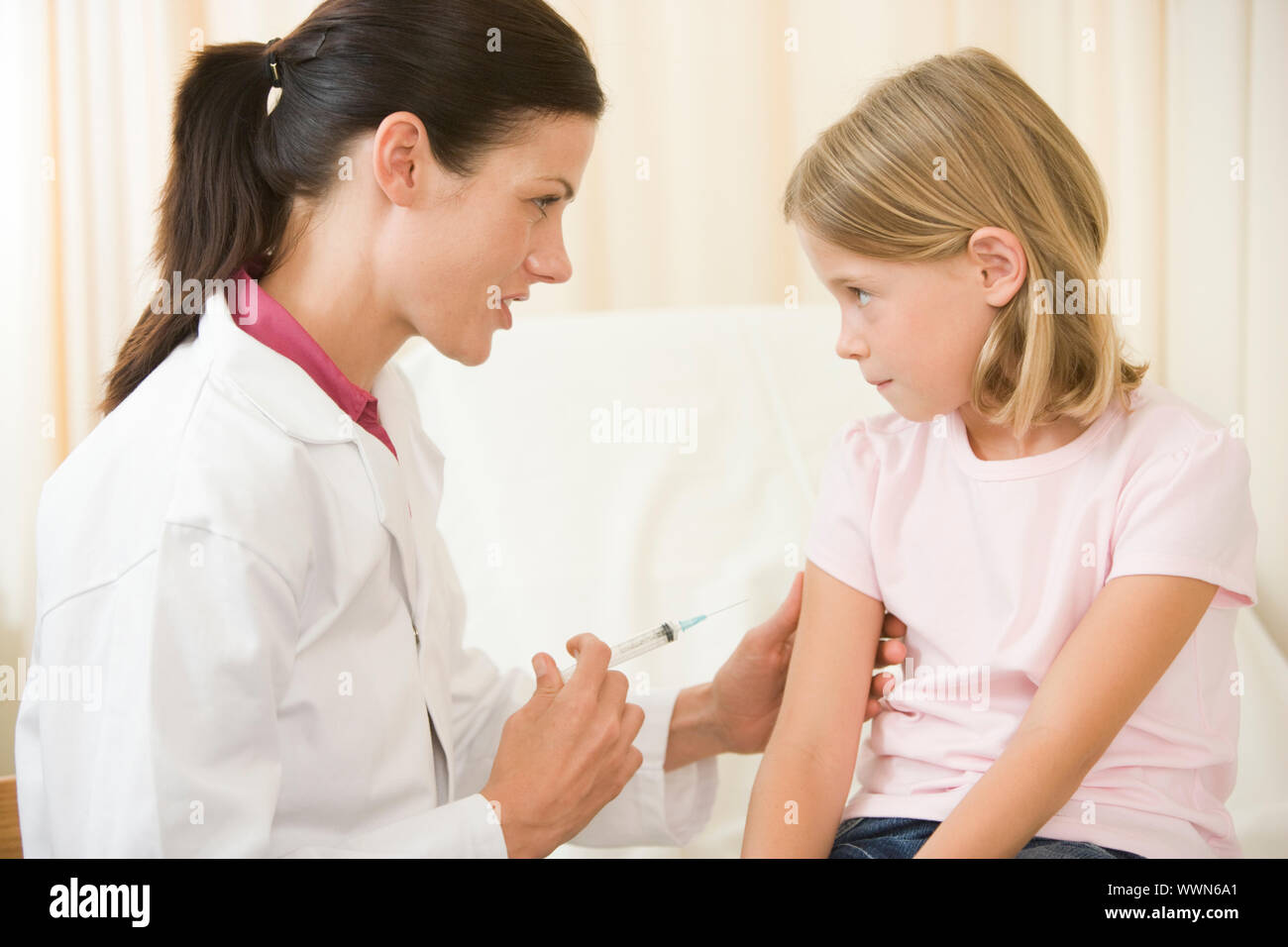 Doctor giving needle to young girl in exam room Stock Photo - Alamy