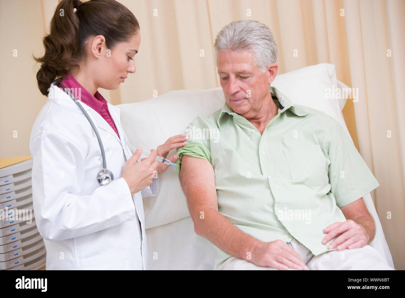 Doctor giving man needle in exam room Stock Photo - Alamy