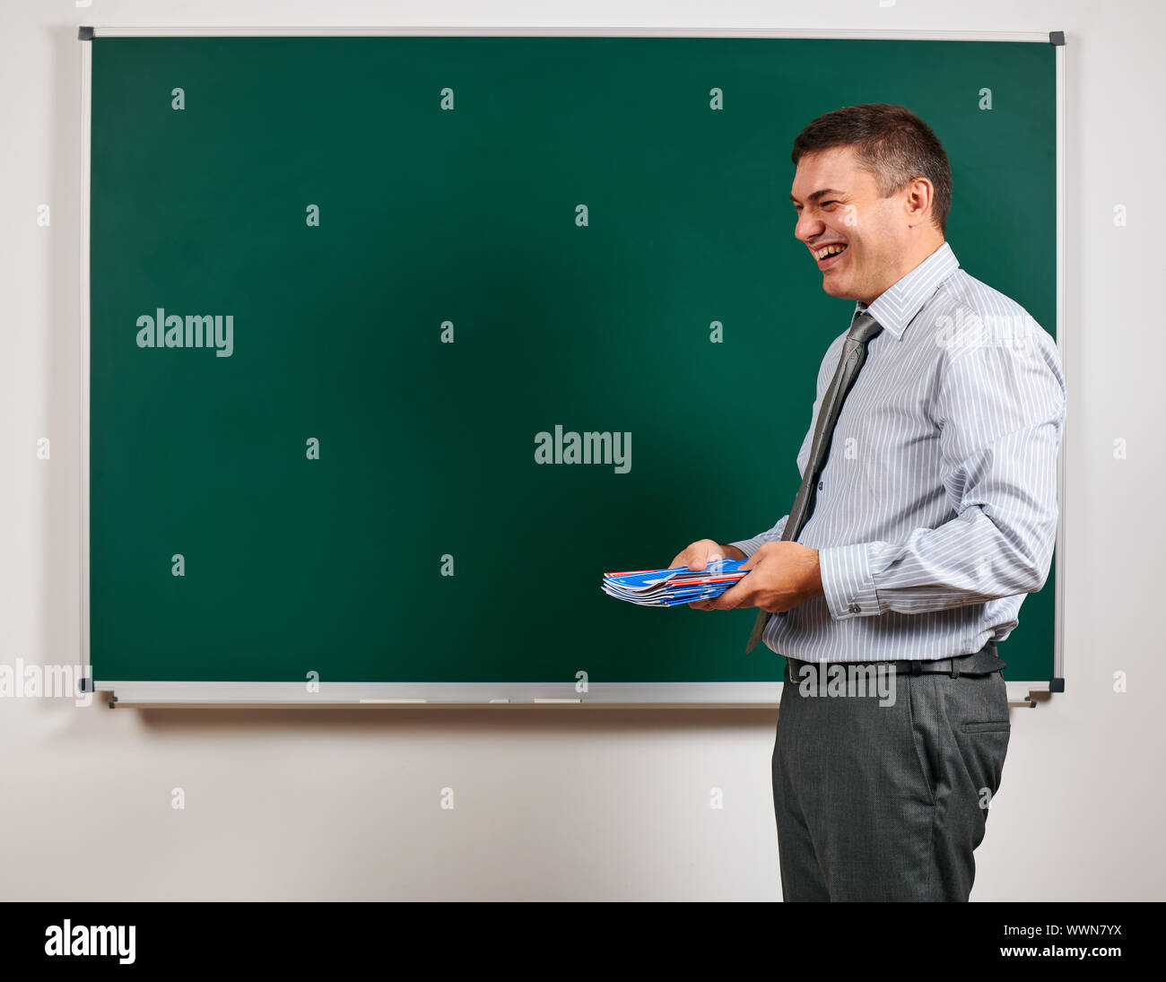 Portrait of a man as a teacher, posing at school board background ...