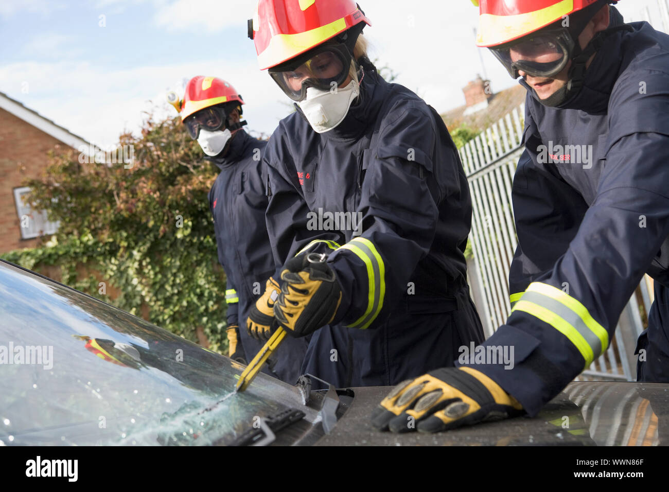 Firefighters breaking a car windscreen to help a car crash victi Stock ...