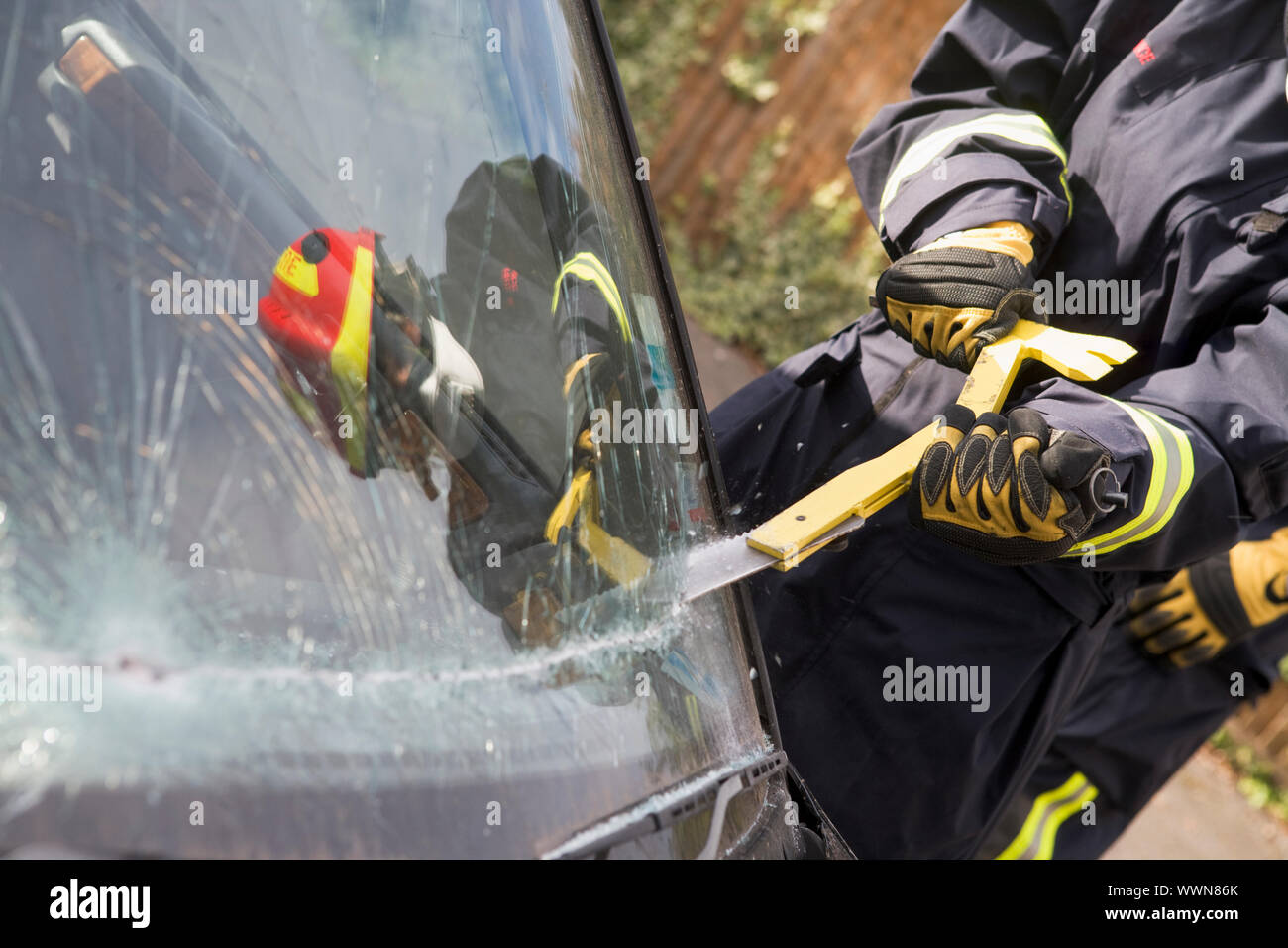 Firefighters breaking a car windscreen to help a car crash victi Stock ...
