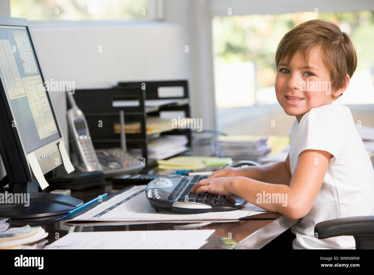 Young boy in home office with computer smiling Stock Photo - Alamy