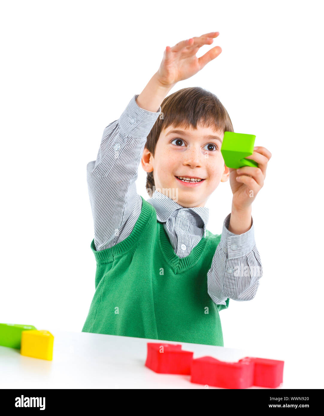 A smiling little boy is building a toy block. Isolated on white ...