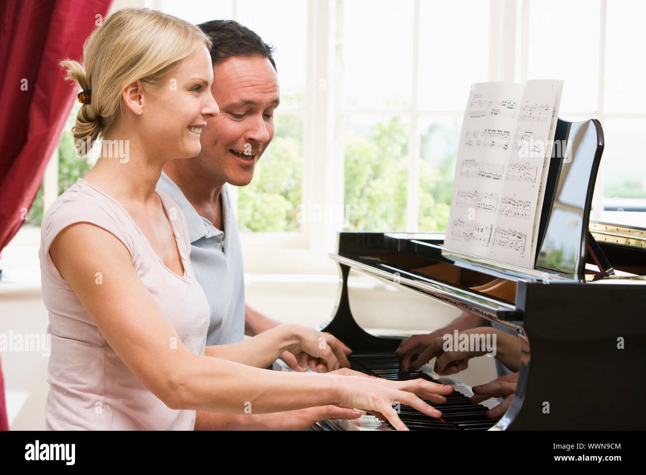 Couple playing piano and smiling Stock Photo - Alamy