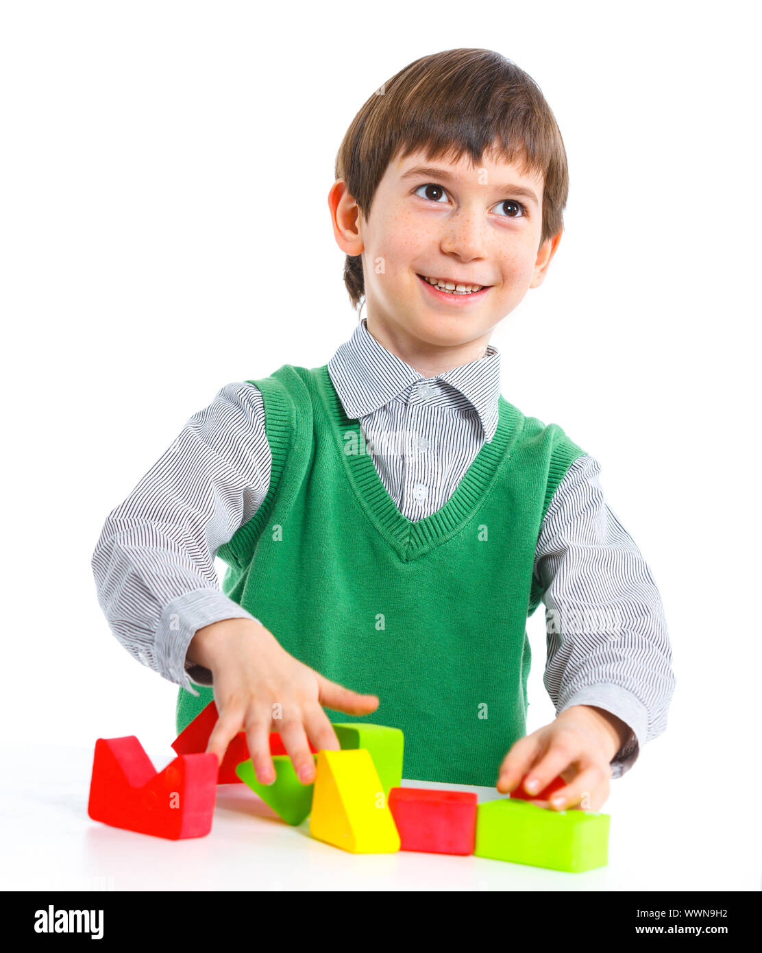A smiling little boy is building a toy block. Isolated on white ...