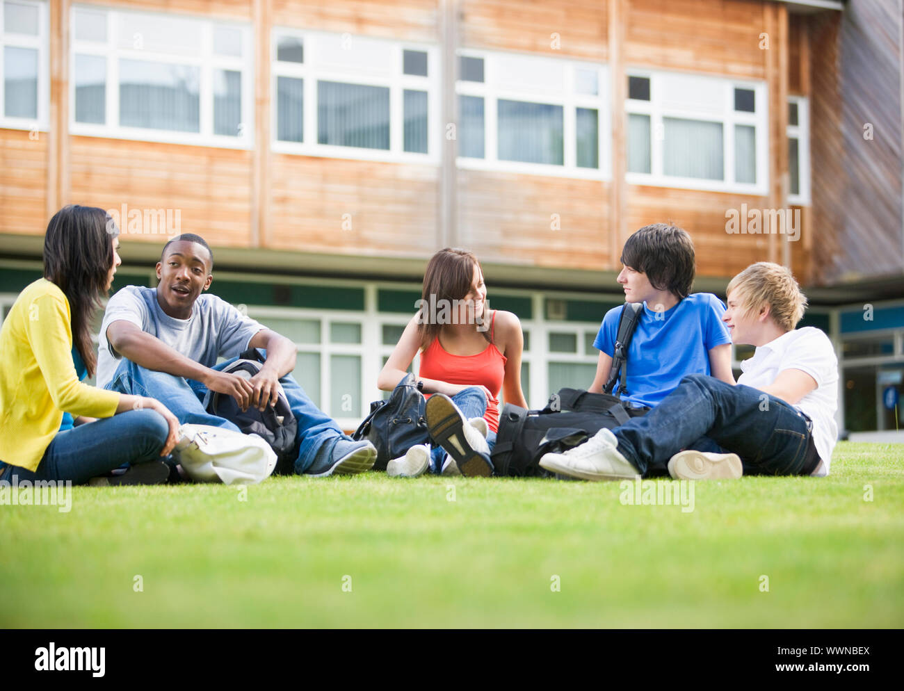 College students sitting and talking on campus lawn Stock Photo - Alamy