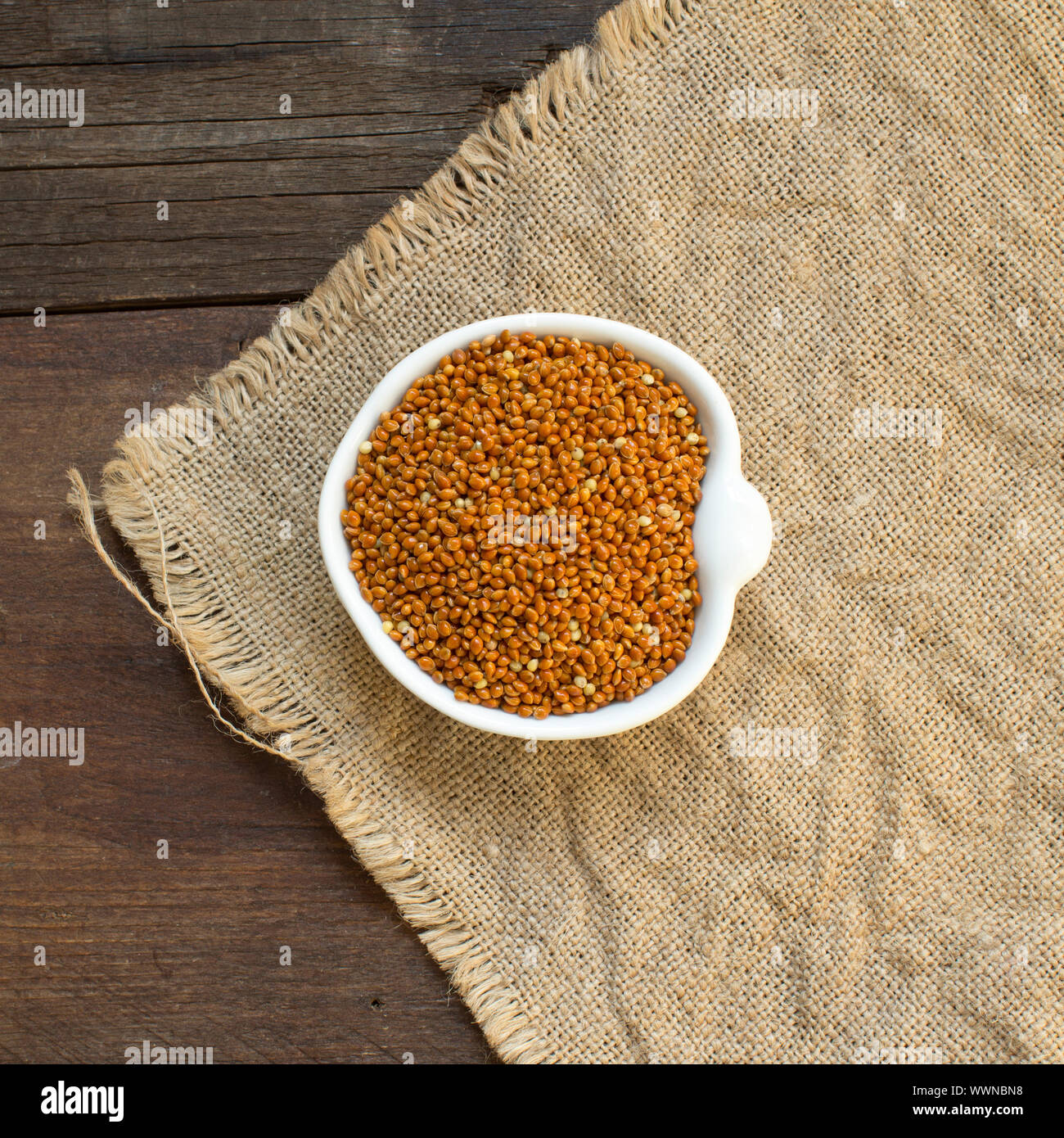 Raw brown millet in a bowl on burlap and wood Stock Photo - Alamy