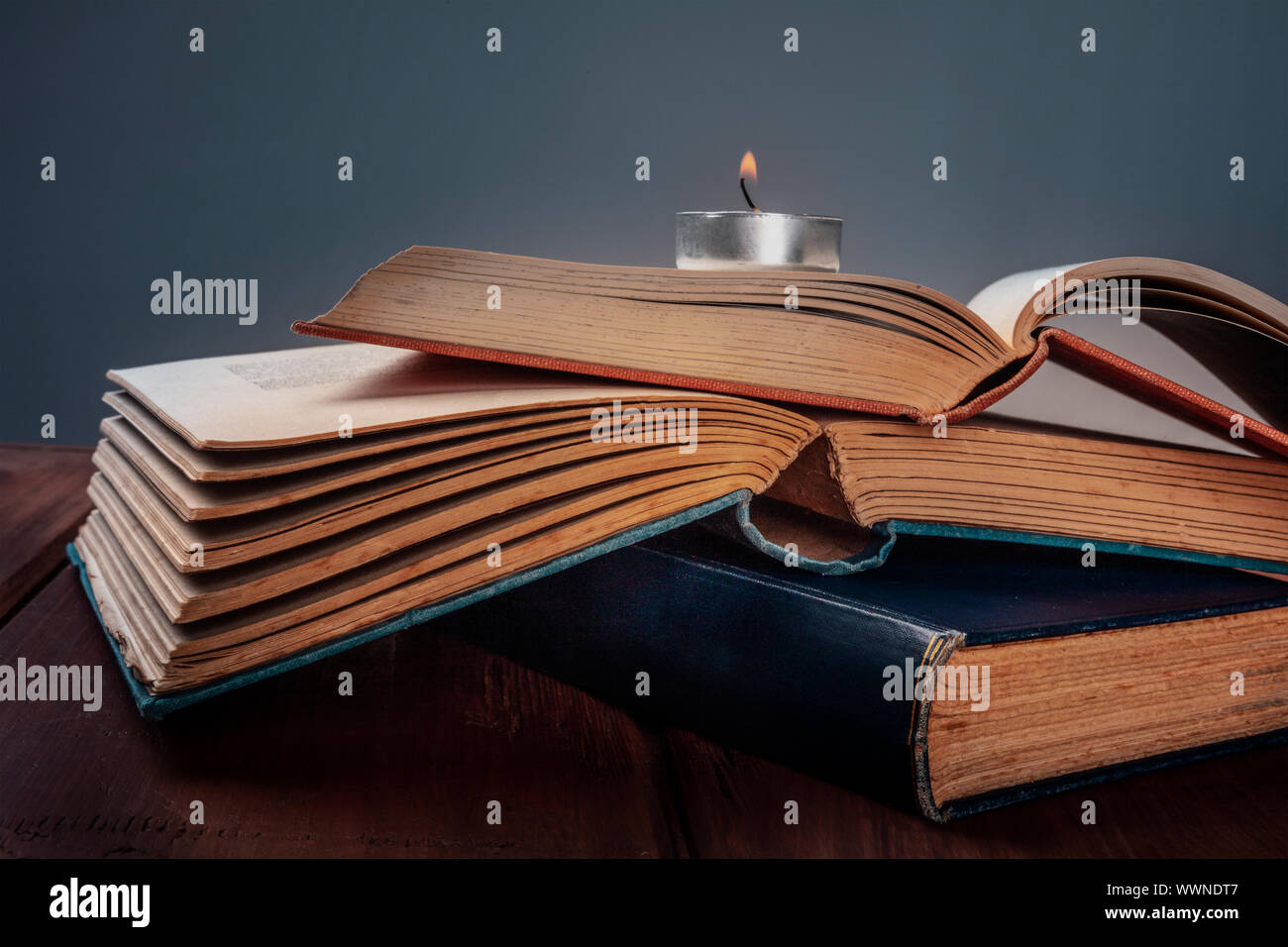 A stack of old books with a burning candle and a place for text ...