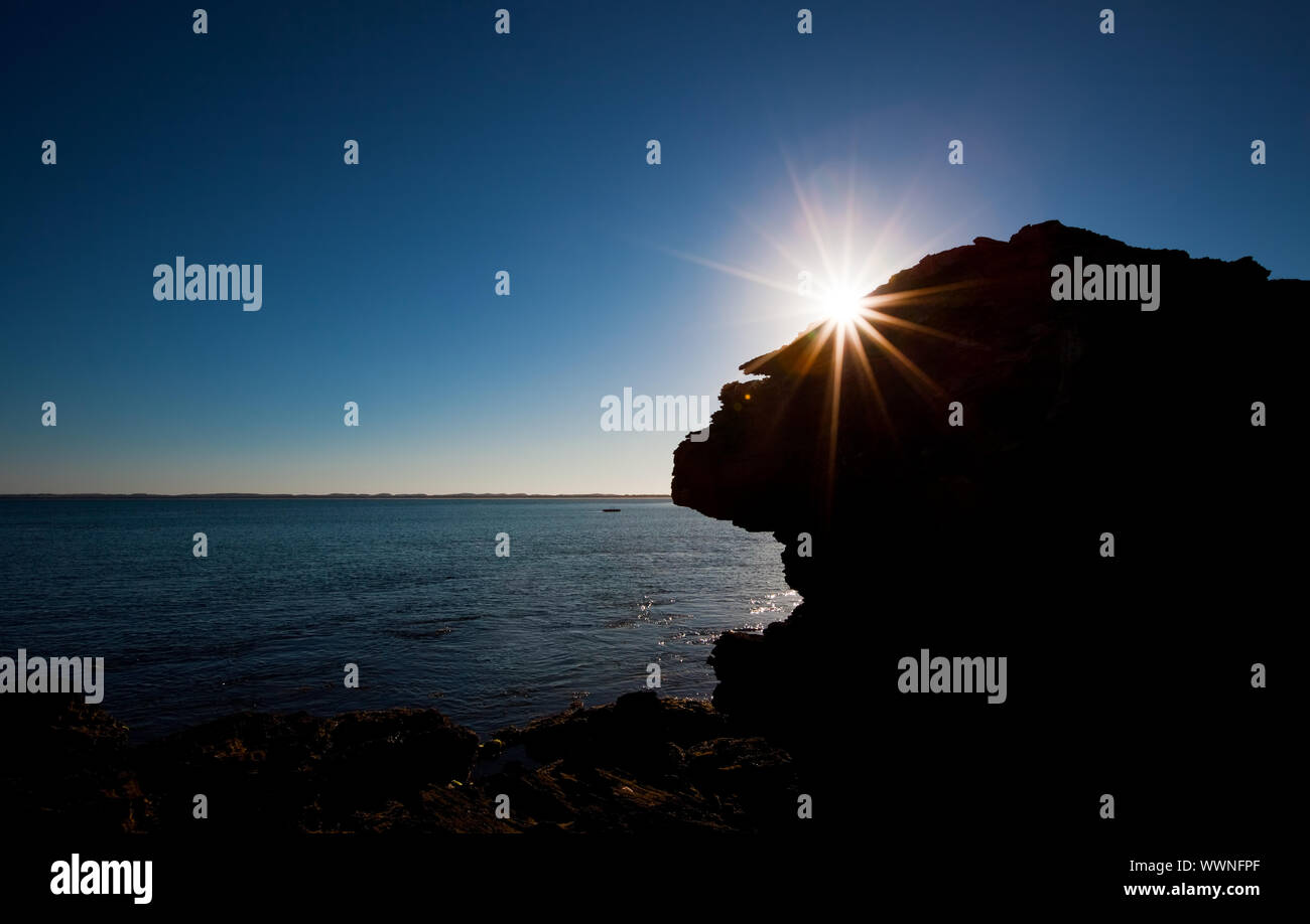 Sun Rising over silhouette of rock Stock Photo - Alamy