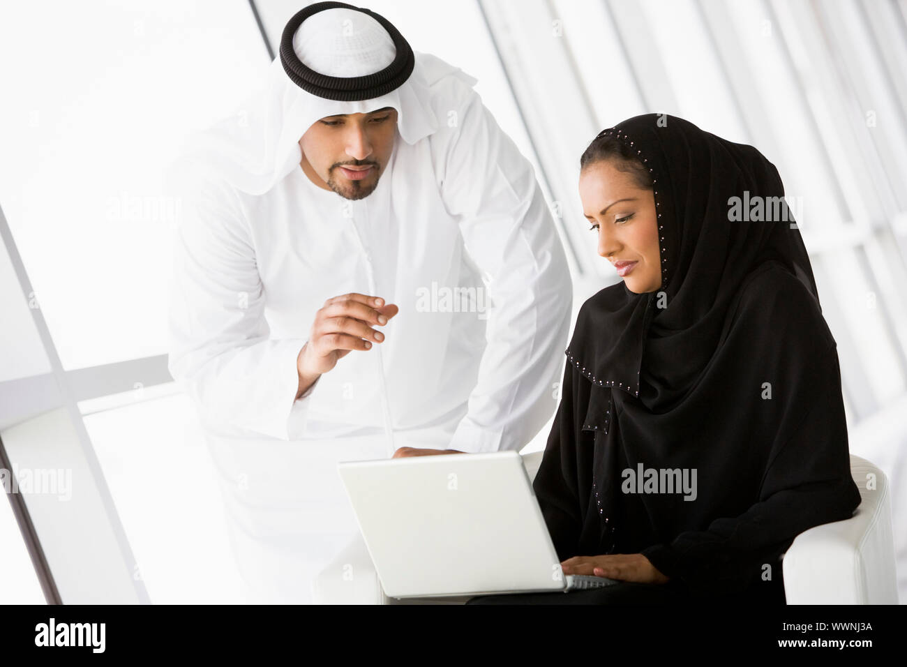 Two people indoors with laptop smiling Stock Photo - Alamy