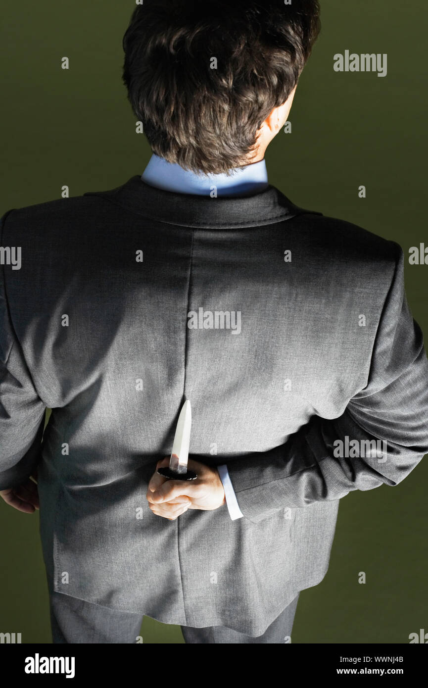 Businessman Holding Knife Behind Back Stock Photo - Alamy