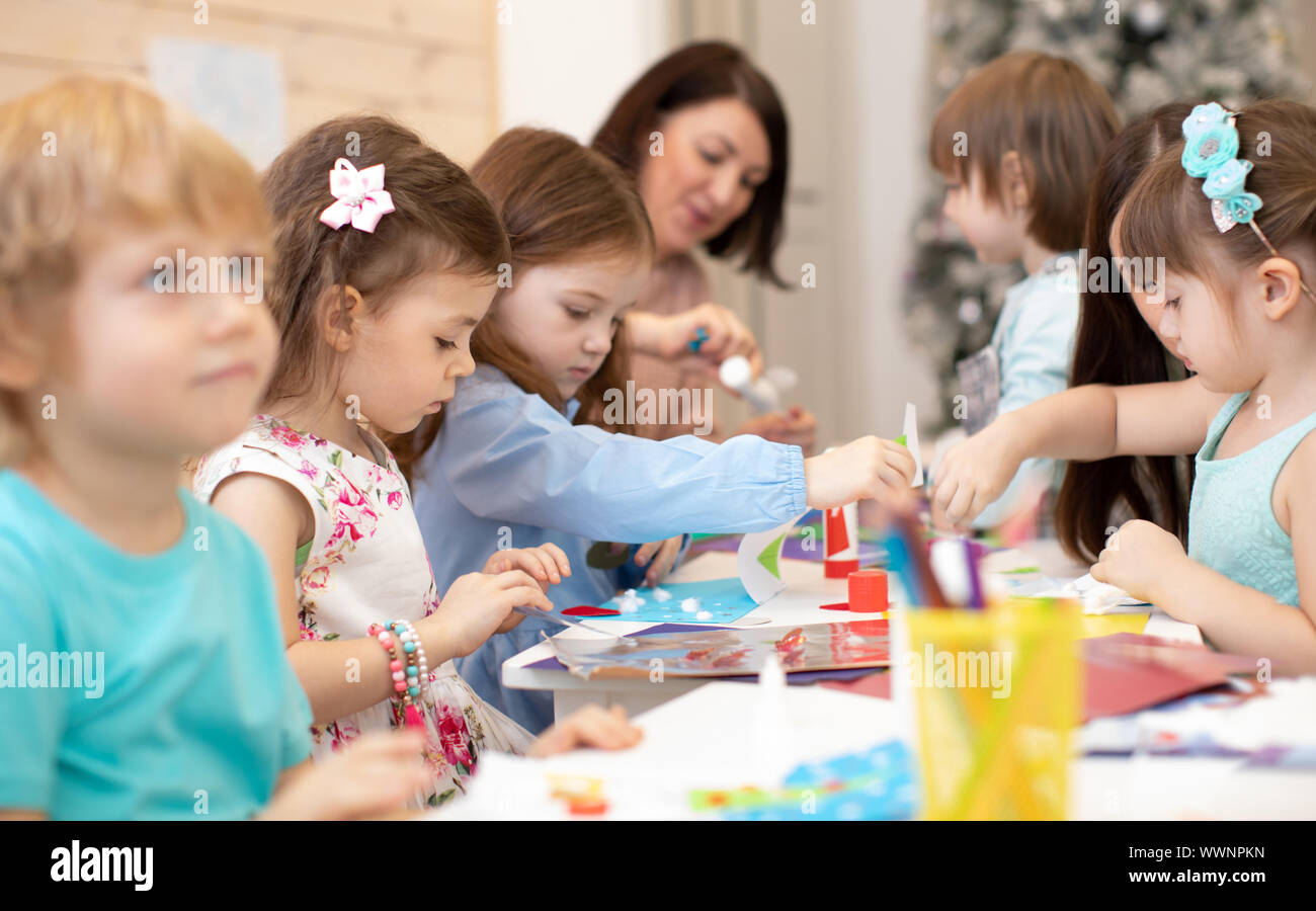 Group of children on hand arts lesson in kindergarten. Teacher helps ...