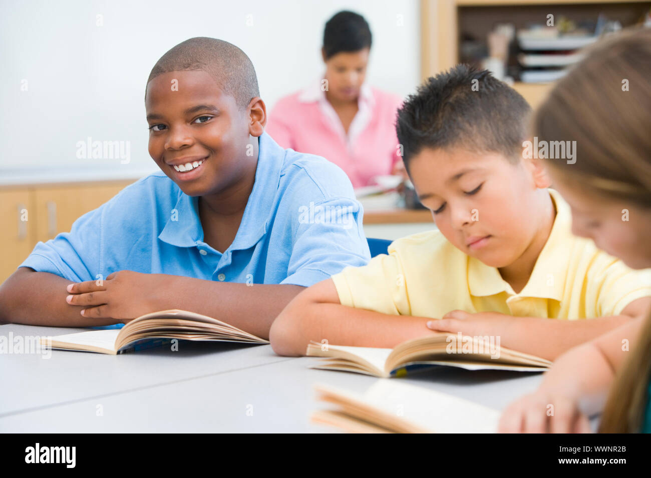 Group of pupils reading books at desk Stock Photo - Alamy
