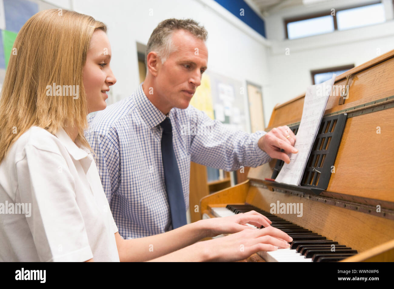 Female student learning piano with teacher in classroom Stock Photo - Alamy
