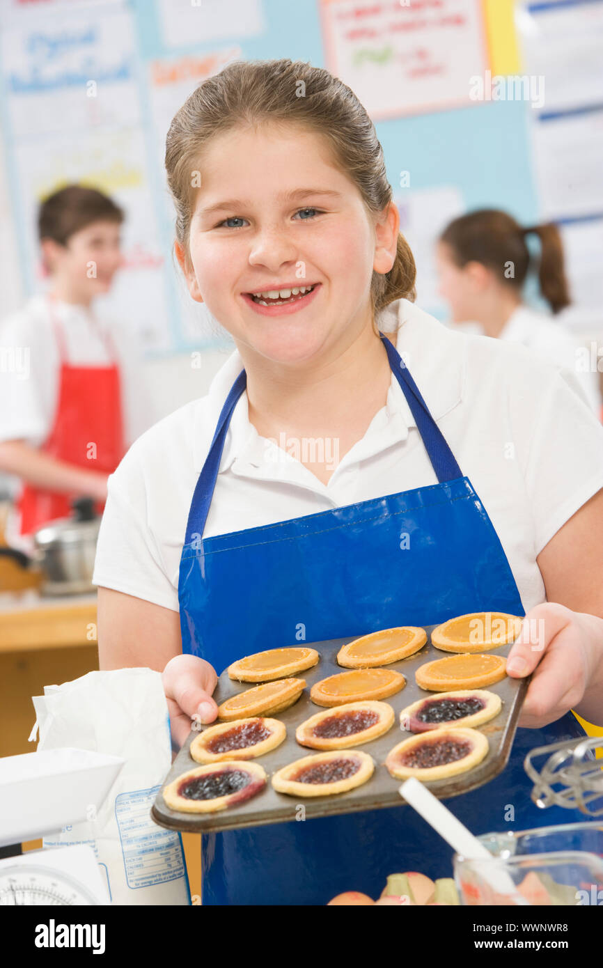 Female student holding a tray of tarts in cooking class Stock Photo - Alamy