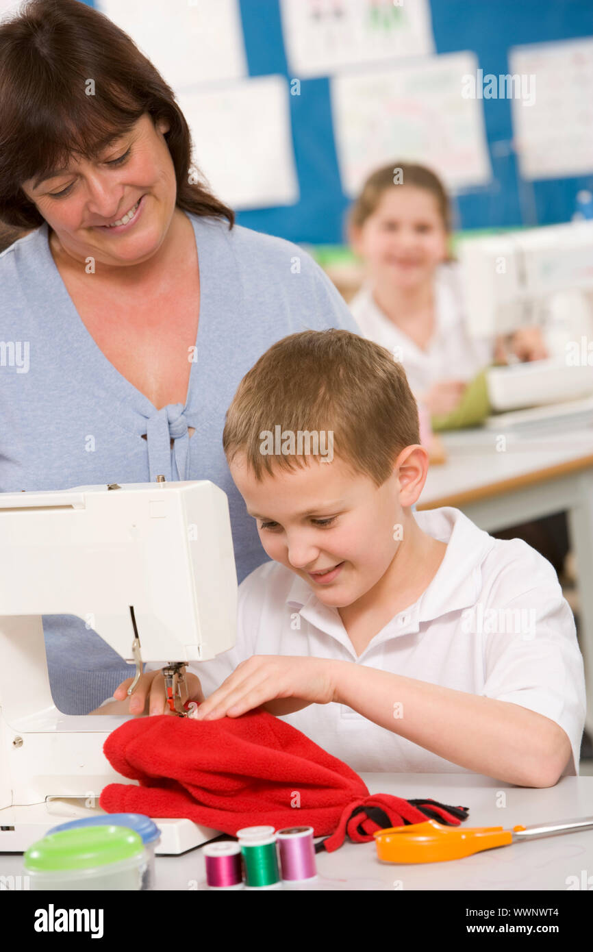 Male student using sewing machine with teacher Stock Photo - Alamy