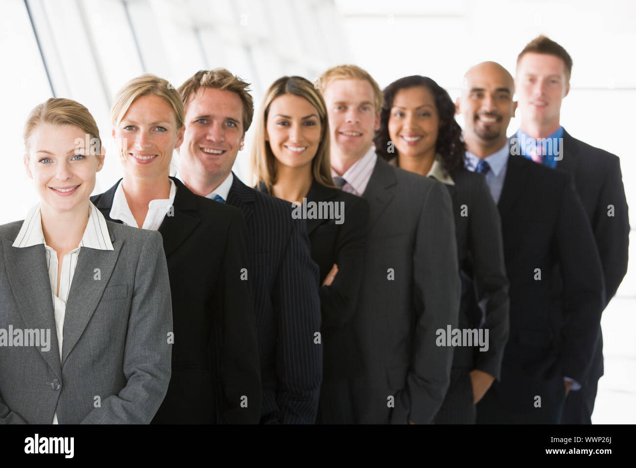 Group of co-workers standing in office space smiling (high key/depth of ...