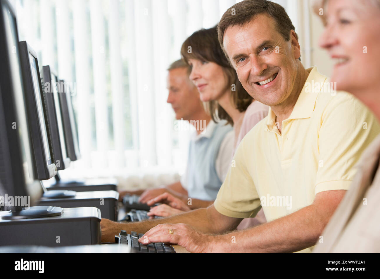 Four people sitting at computer terminals (depth of field/high key ...