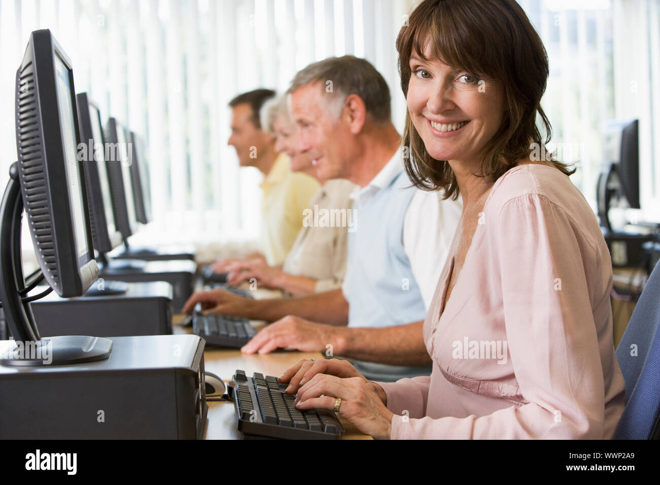 Four people sitting at computer terminals (depth of field/high key ...