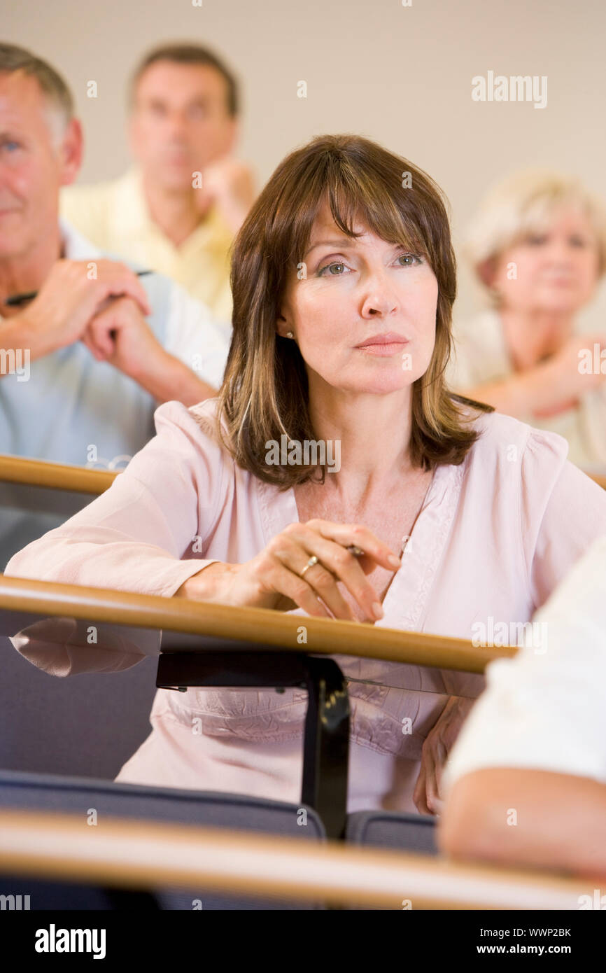 Woman sitting in adult classroom with students in background (selective ...