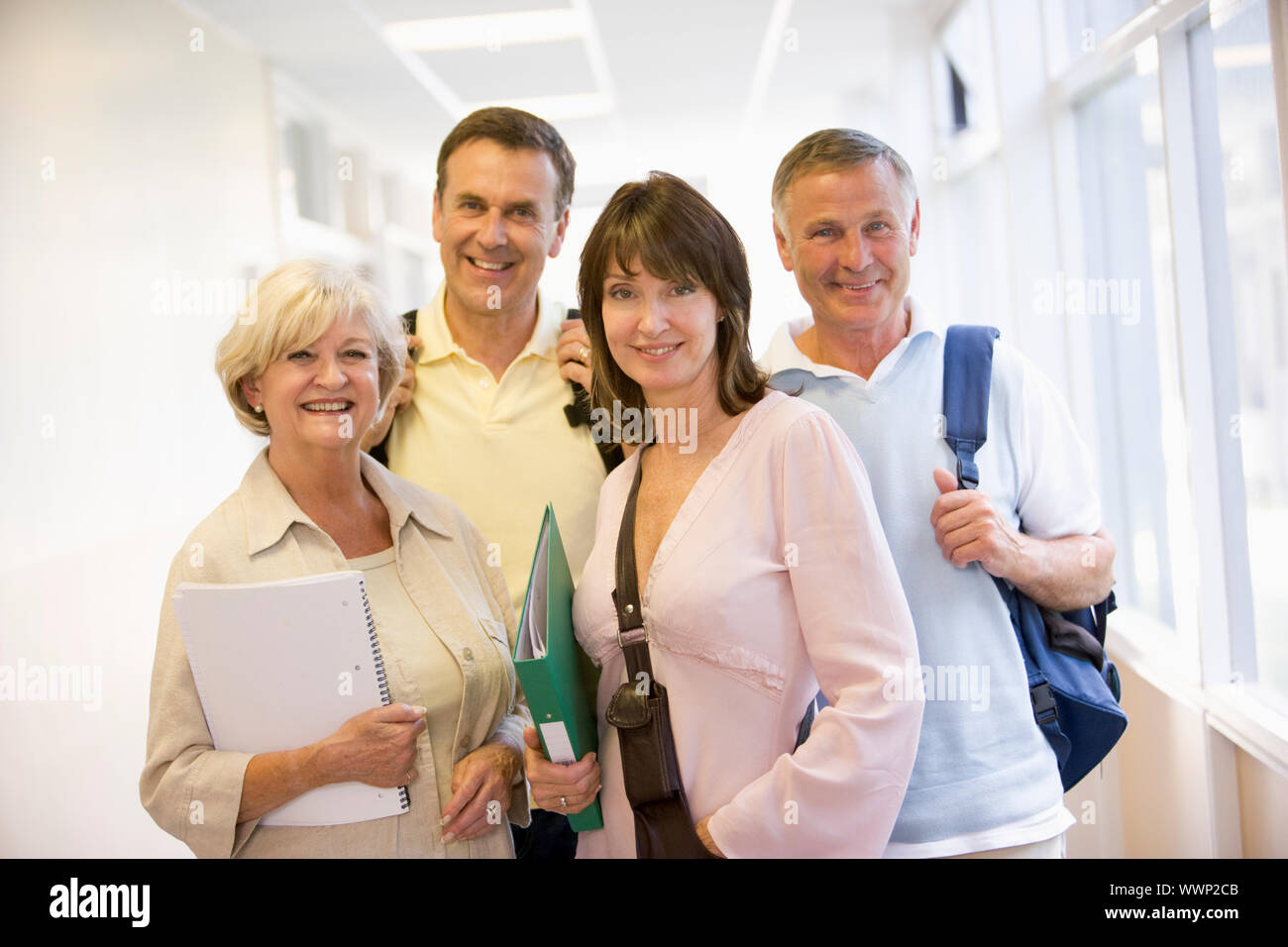 Four people standing in corridor with books (high key Stock Photo - Alamy