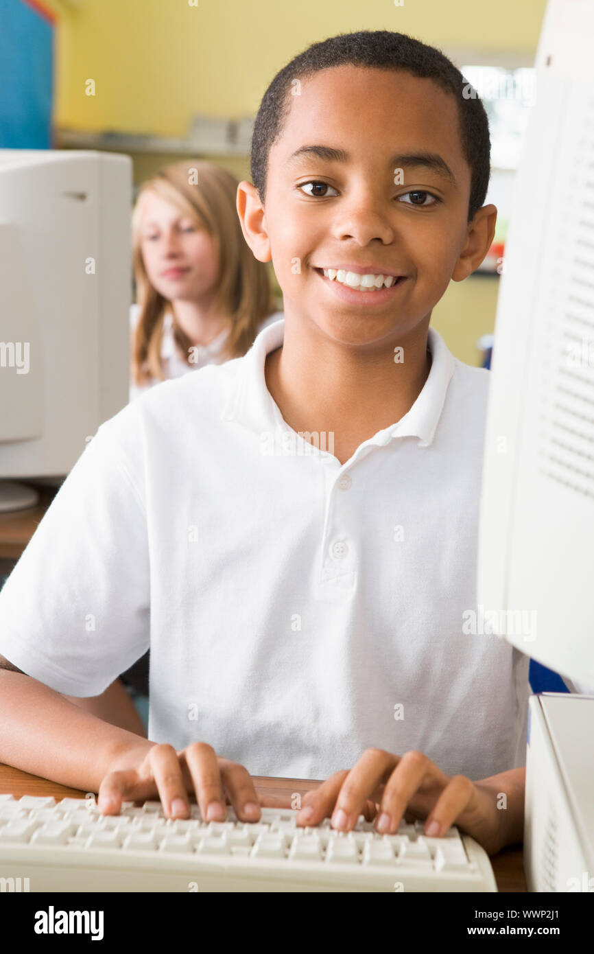 Student at computer terminal typing with student in background ...