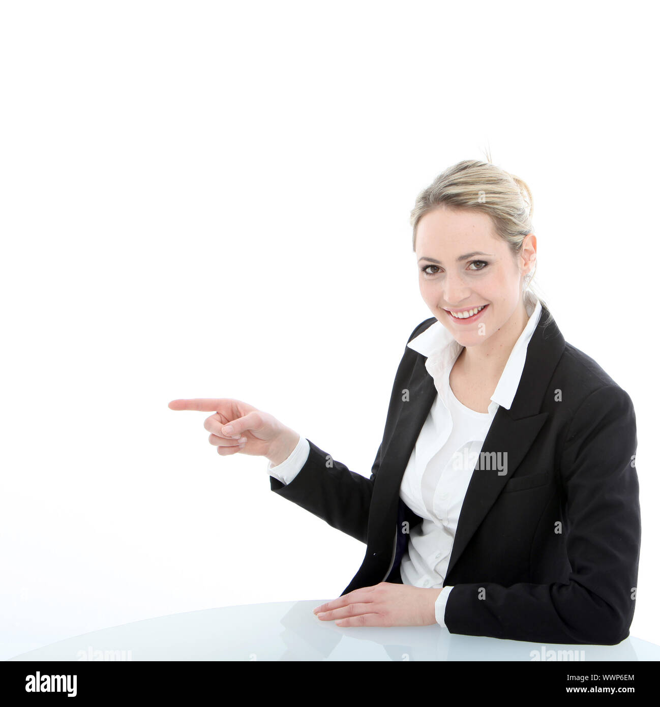 Smiling attractive professional woman seated at a table pointing to her ...