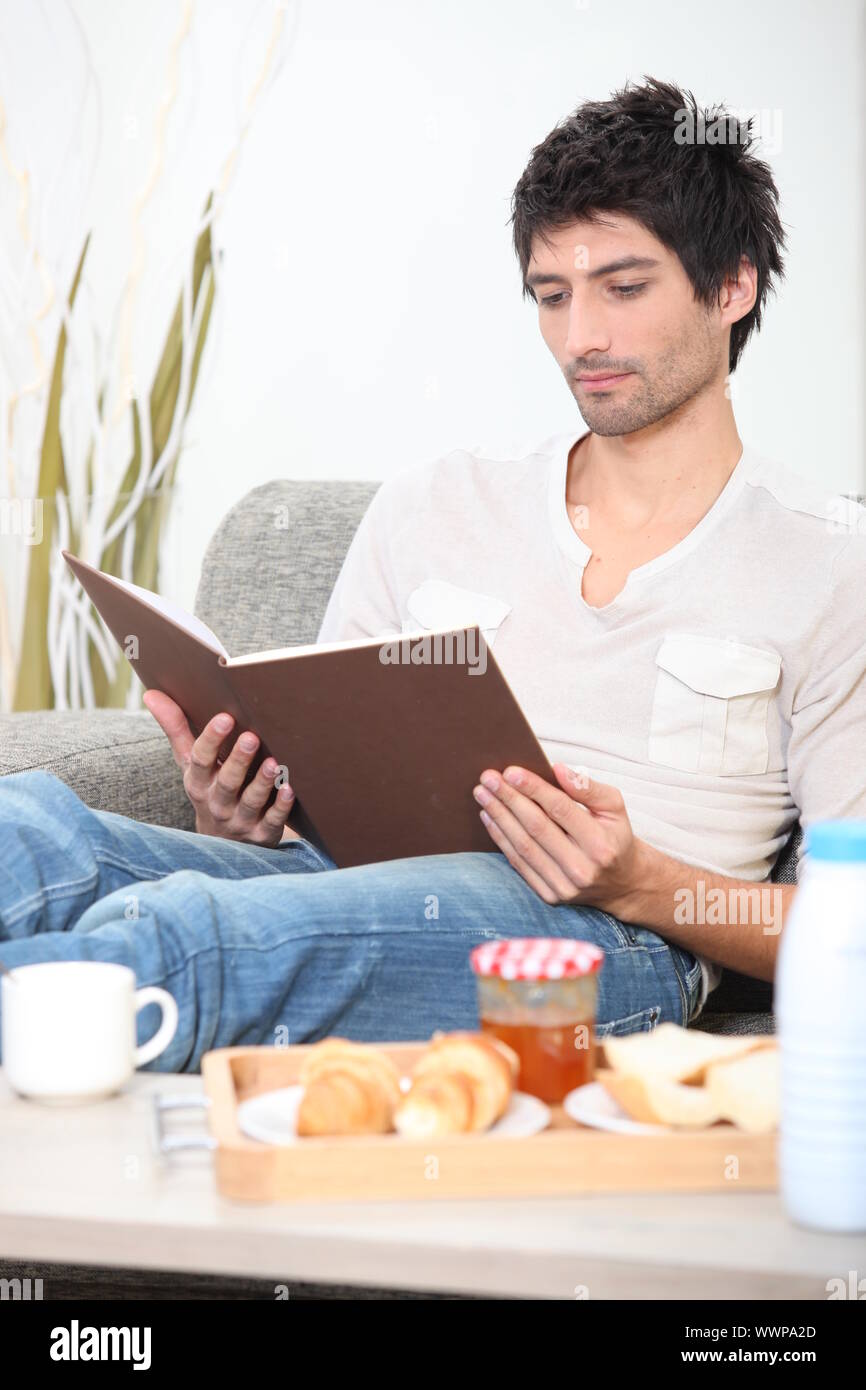 Man reading book whilst eating breakfast Stock Photo - Alamy