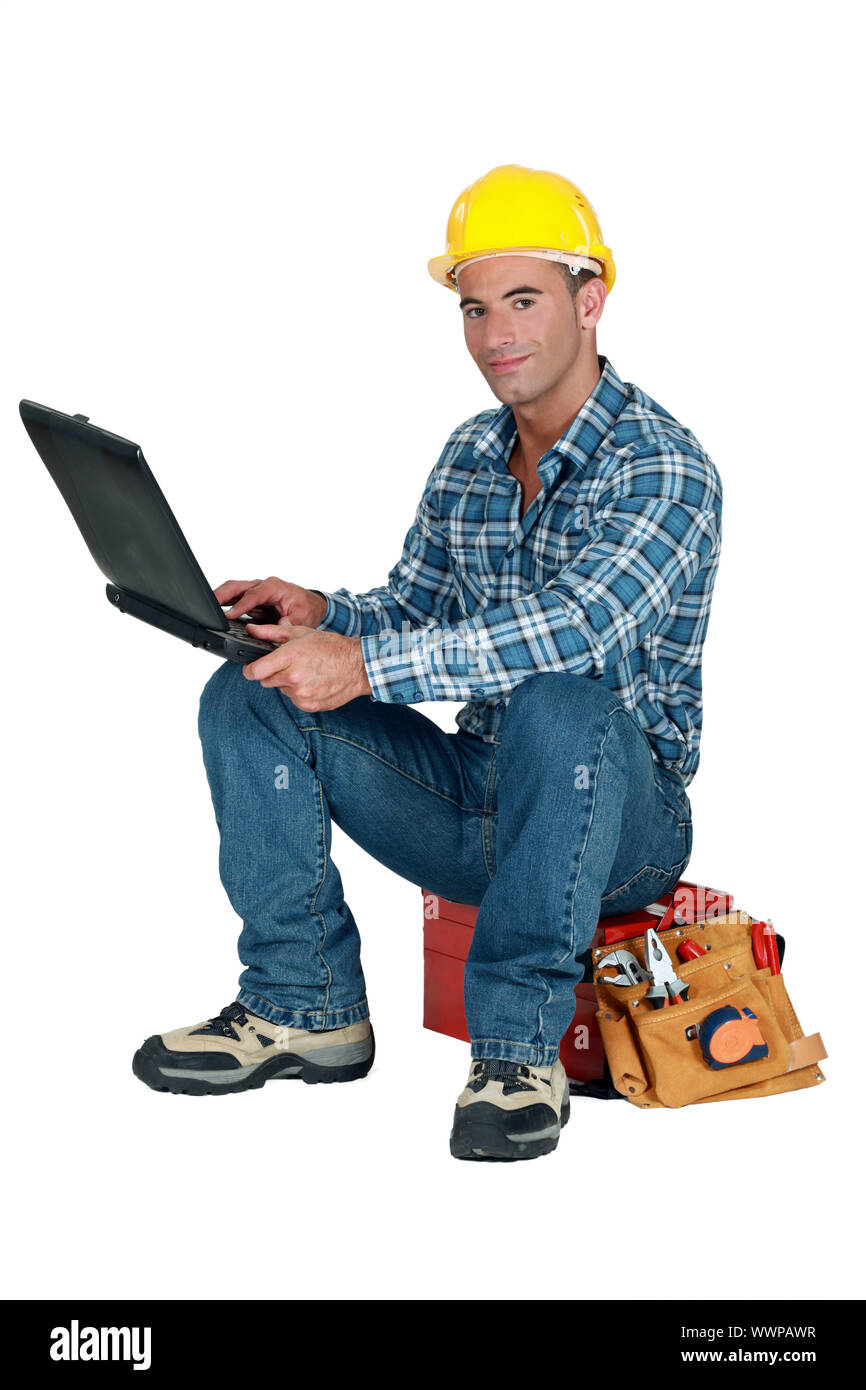 Tradesman sitting on his toolbox and using his laptop Stock Photo - Alamy