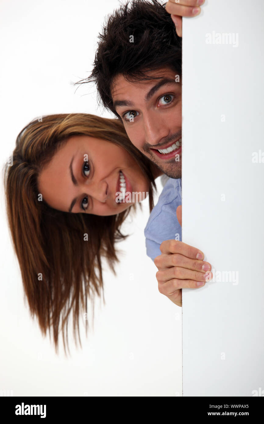 young woman and man hiding behind the door Stock Photo - Alamy