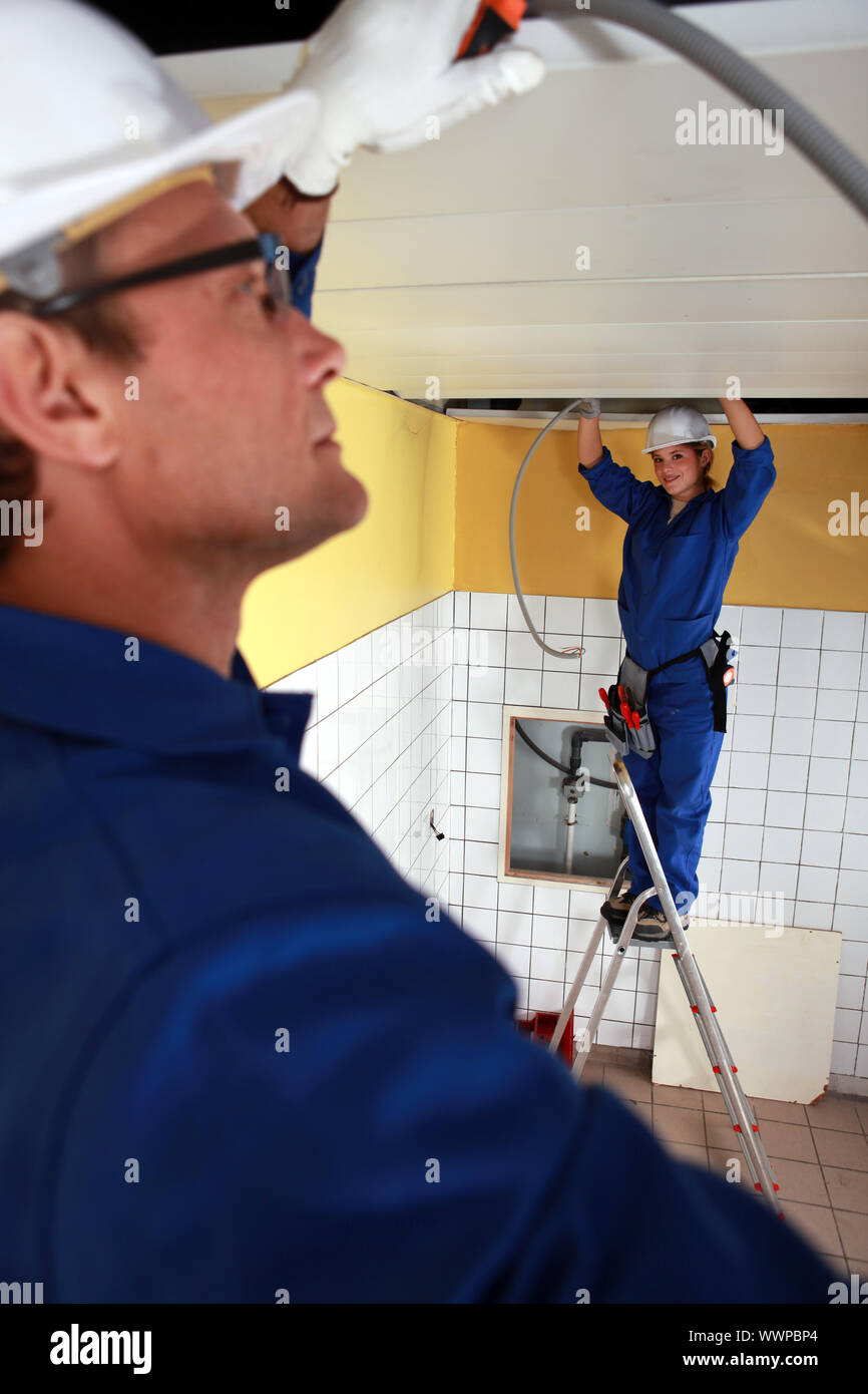 Electrical team wiring a tiled room Stock Photo - Alamy