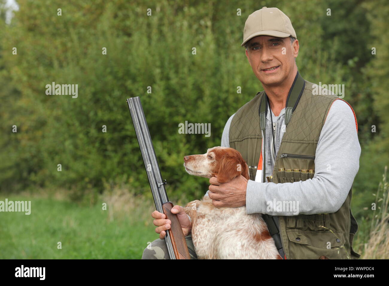Hunter crouching by dog Stock Photo - Alamy
