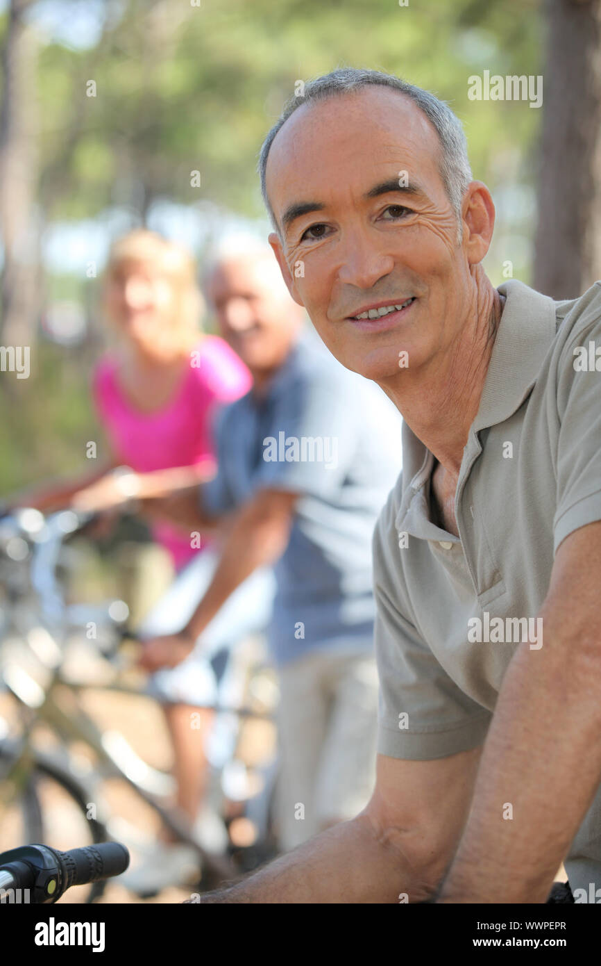 Older man riding a bike in the forest with friends Stock Photo - Alamy