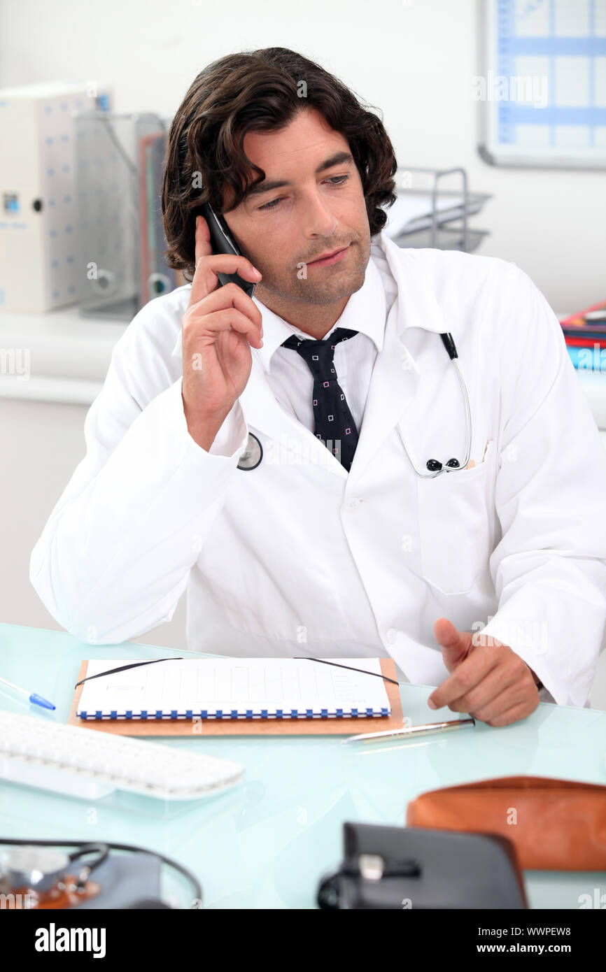Doctor using a telephone at a desk Stock Photo - Alamy