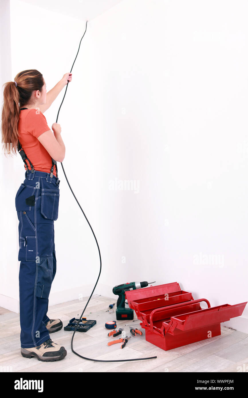 Female electrician pulling cable through wall Stock Photo - Alamy