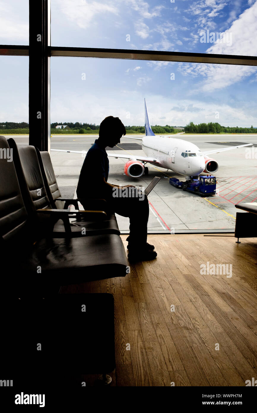 A young man using a laptop in an airport terminal Stock Photo - Alamy