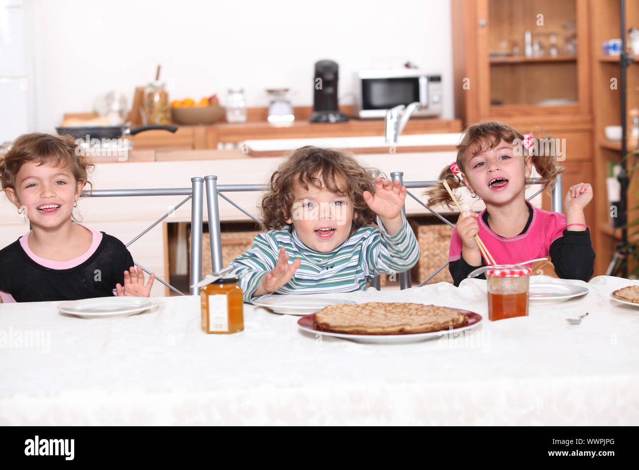 Three children gathered around breakfast table Stock Photo - Alamy
