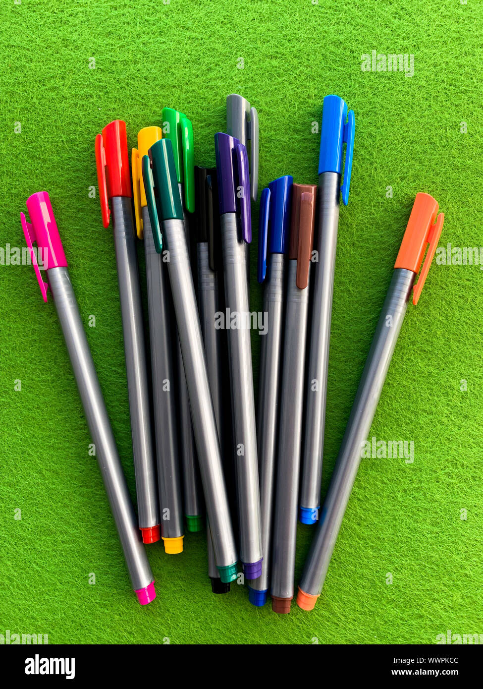 Top view, multi colored pens at green background Stock Photo - Alamy