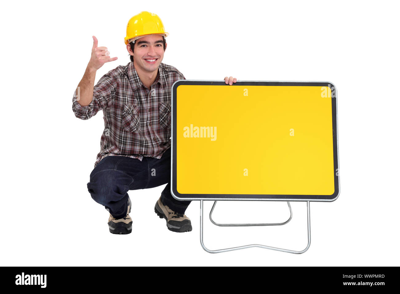Tradesman squatting next to a traffic sign Stock Photo - Alamy