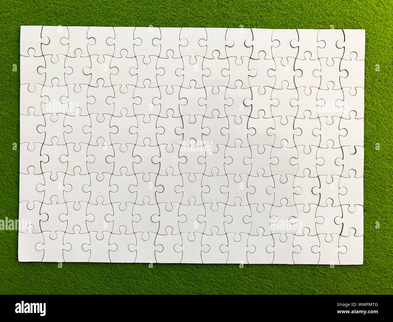 Top view, white puzzle on green background Stock Photo - Alamy