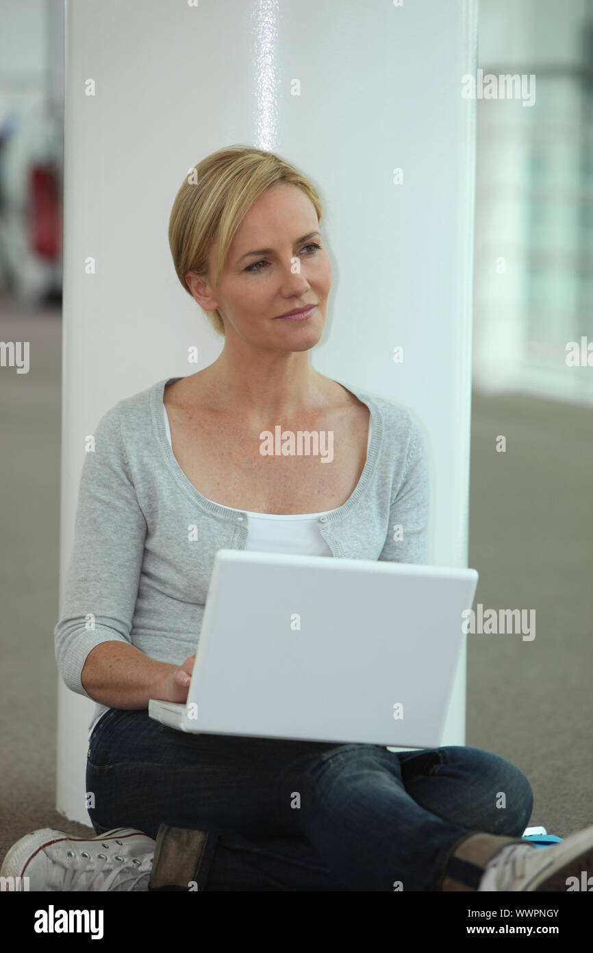 Casually dressed woman using a laptop computer in a public space Stock ...