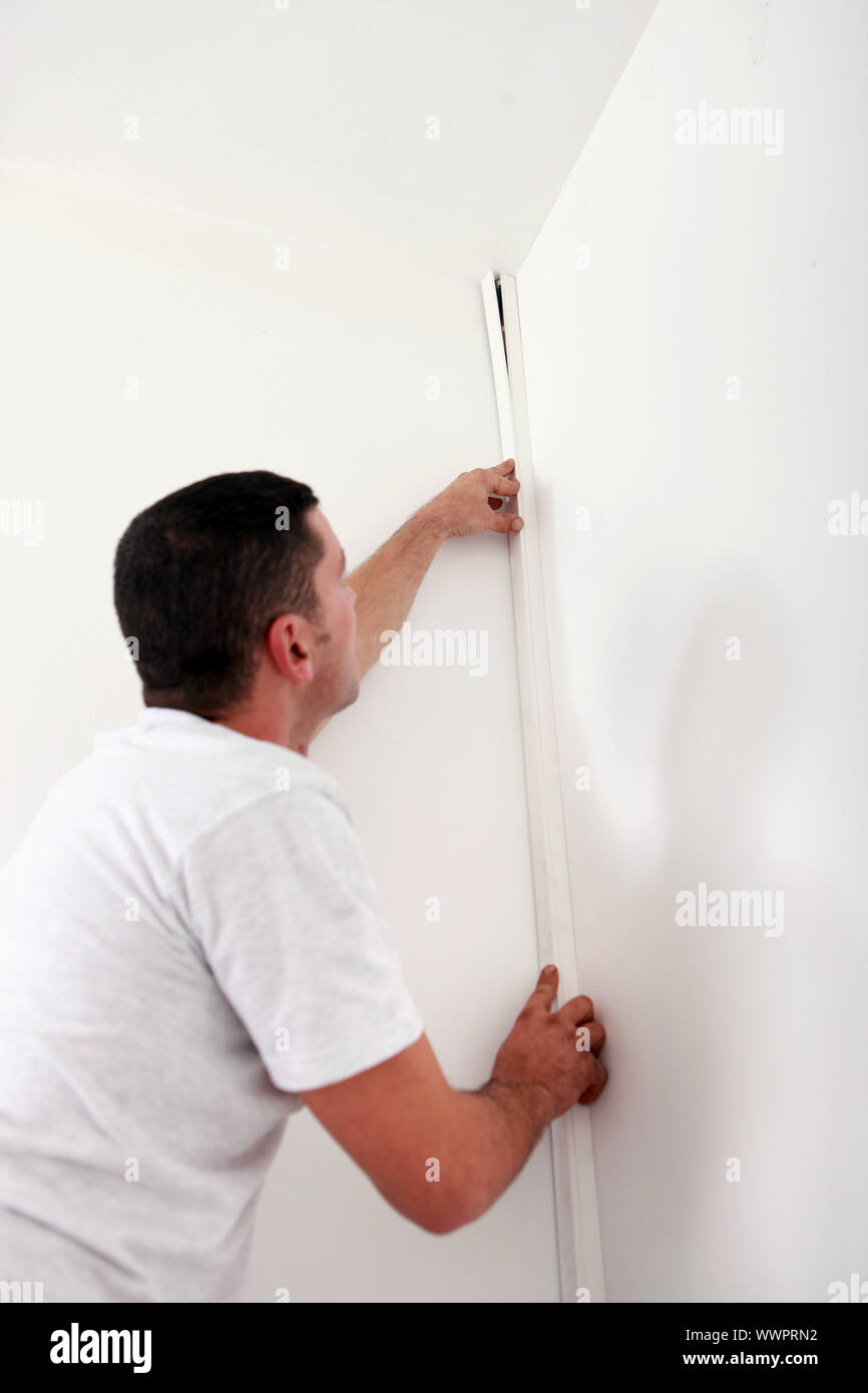 handyman hiding a cable with a plinth Stock Photo - Alamy