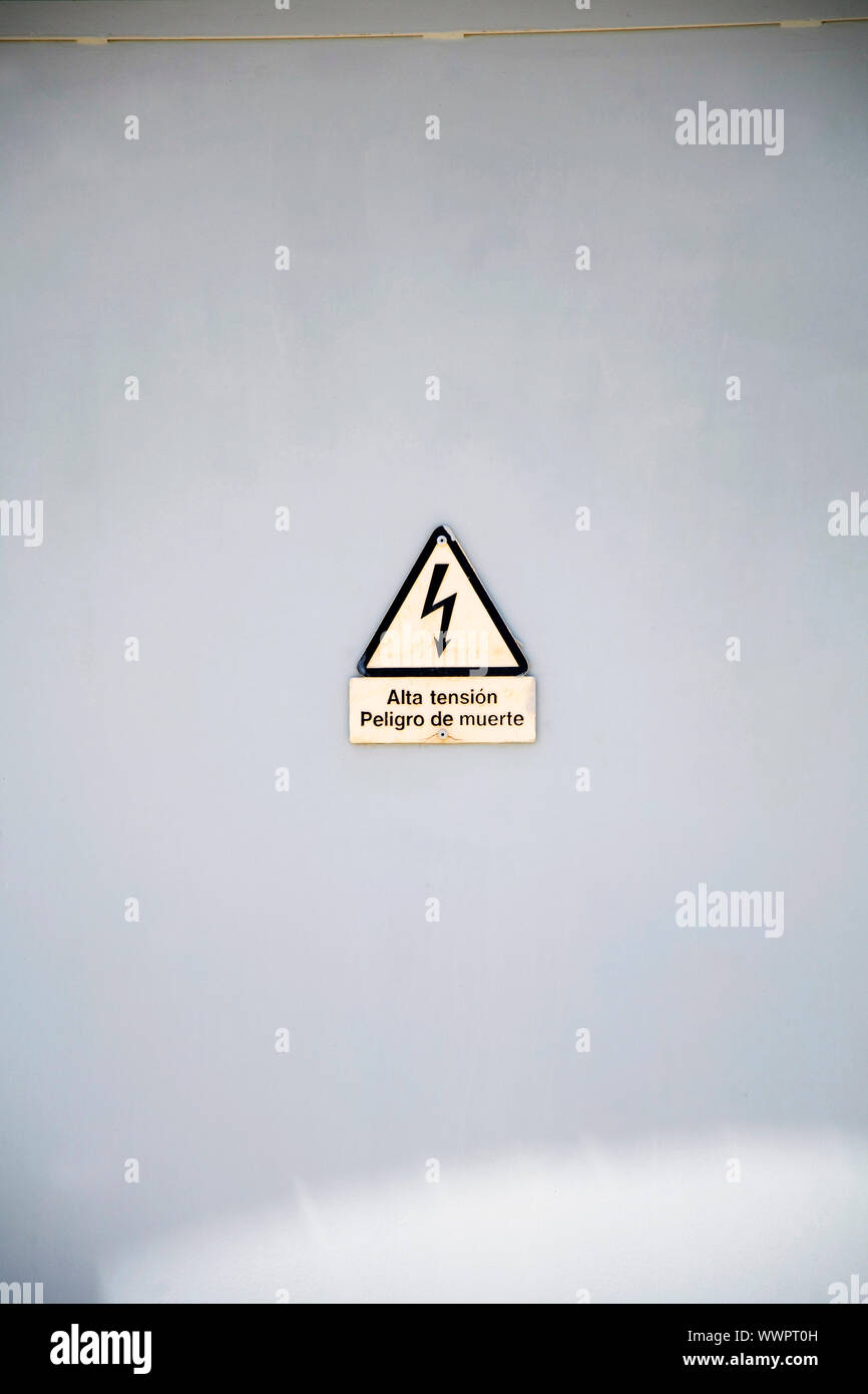 danger high tension sign on a grey wall Stock Photo - Alamy