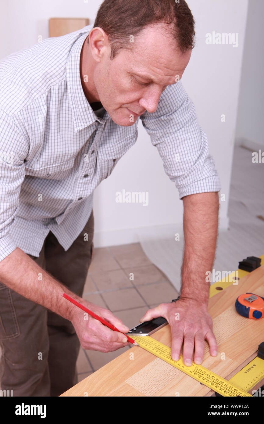 Man measuring plank of wood Stock Photo - Alamy
