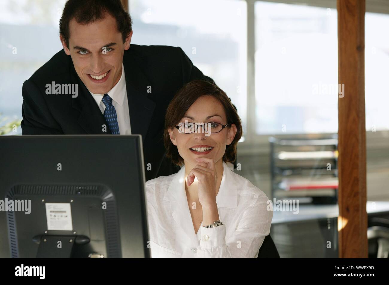 Co-workers in front of desktop computer Stock Photo - Alamy