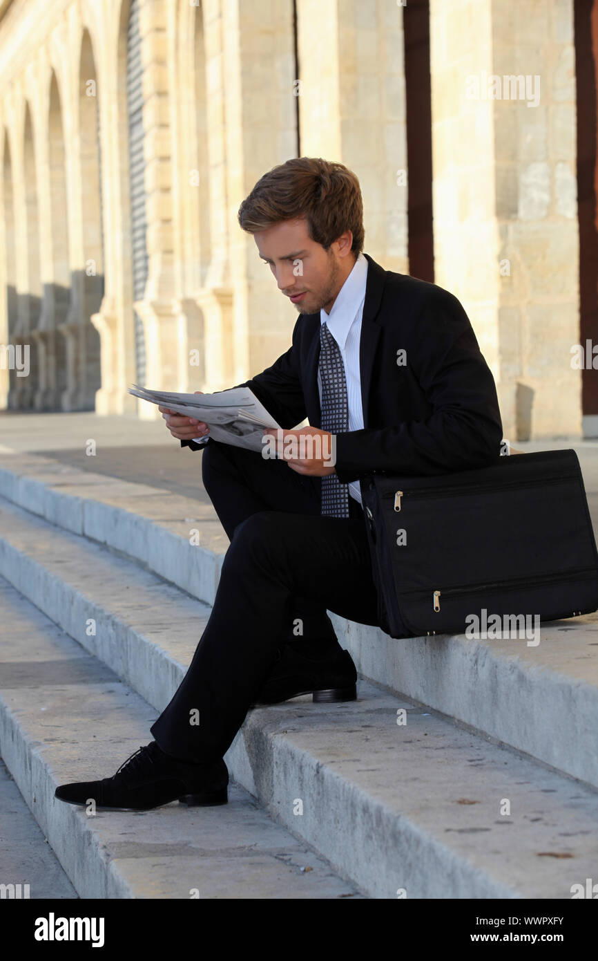 Student in law reading newspaper on stairs Stock Photo - Alamy