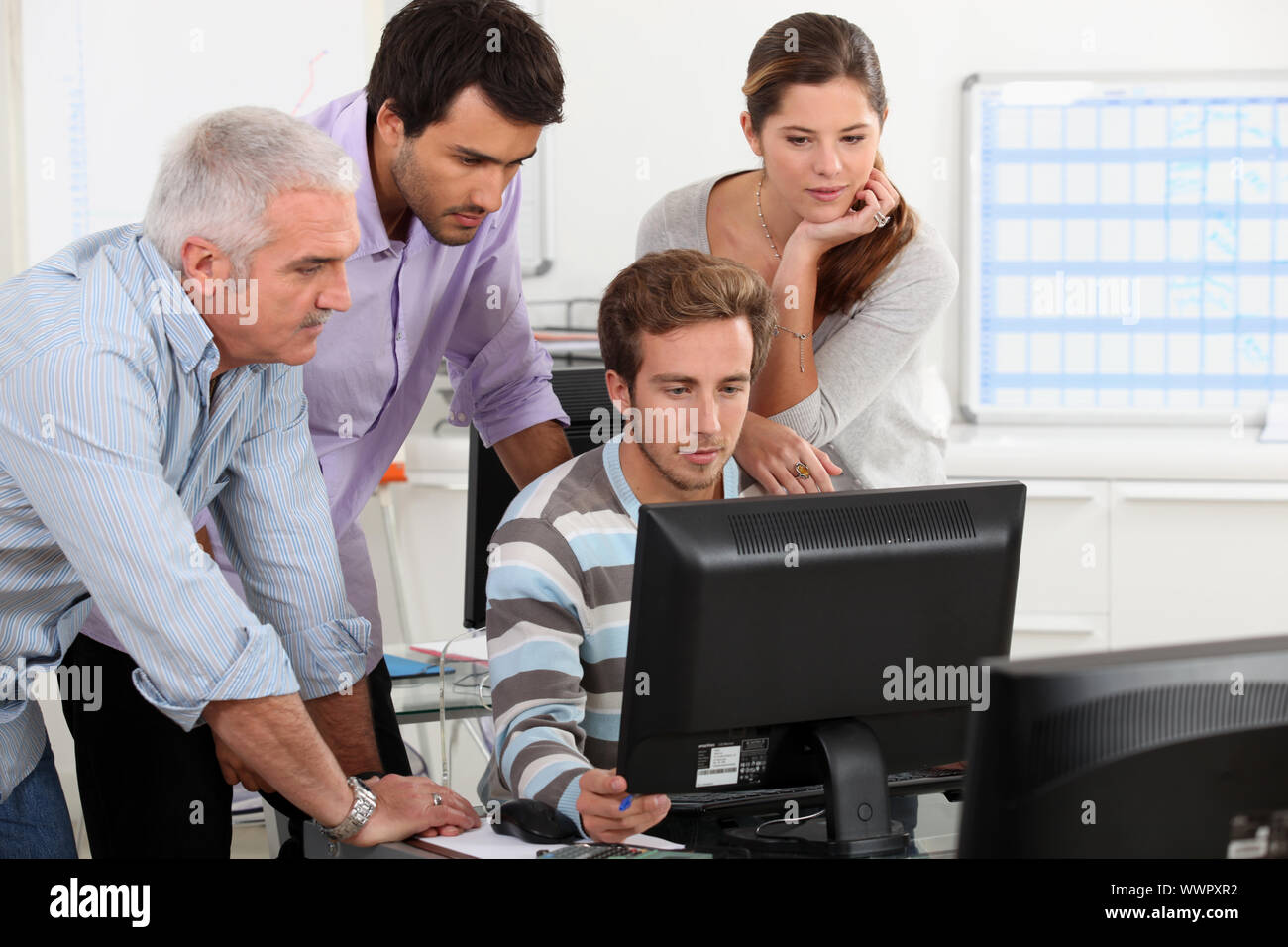Adults around computer Stock Photo - Alamy