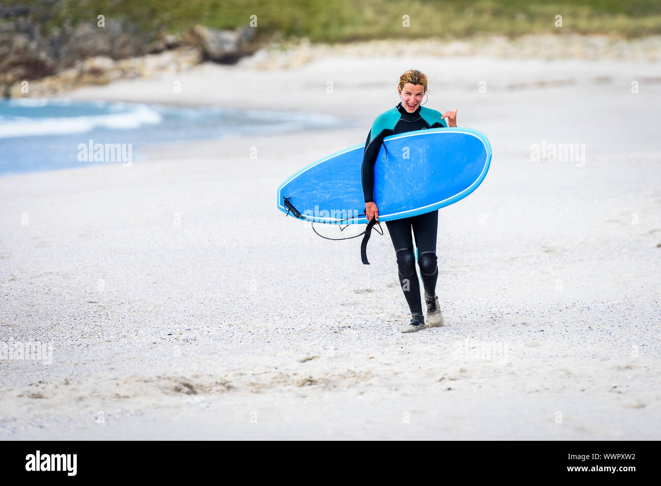 Surfer woman with surfboard is walking and watching the waves. Girl in ...