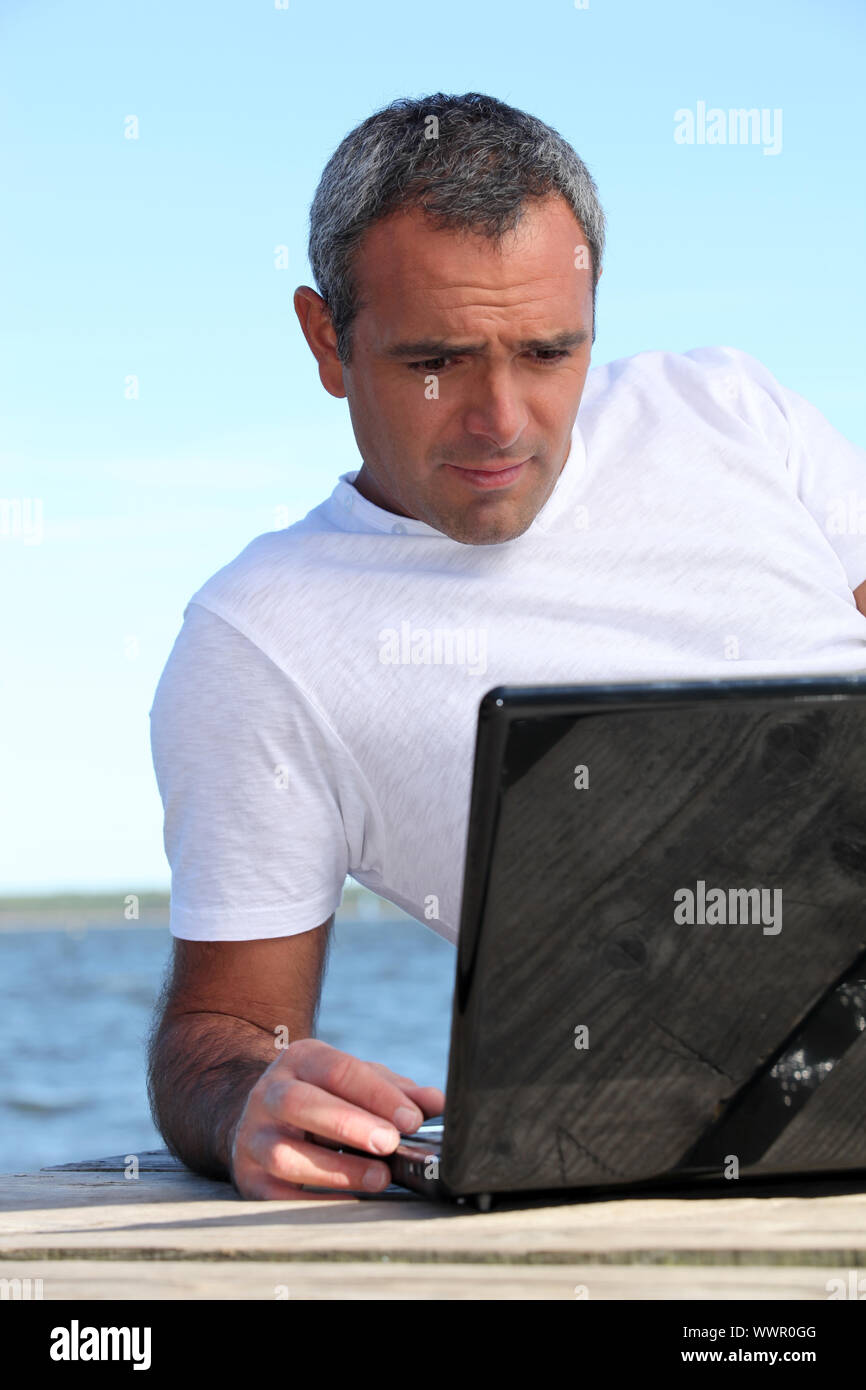 Man using his laptop by the ocean Stock Photo - Alamy