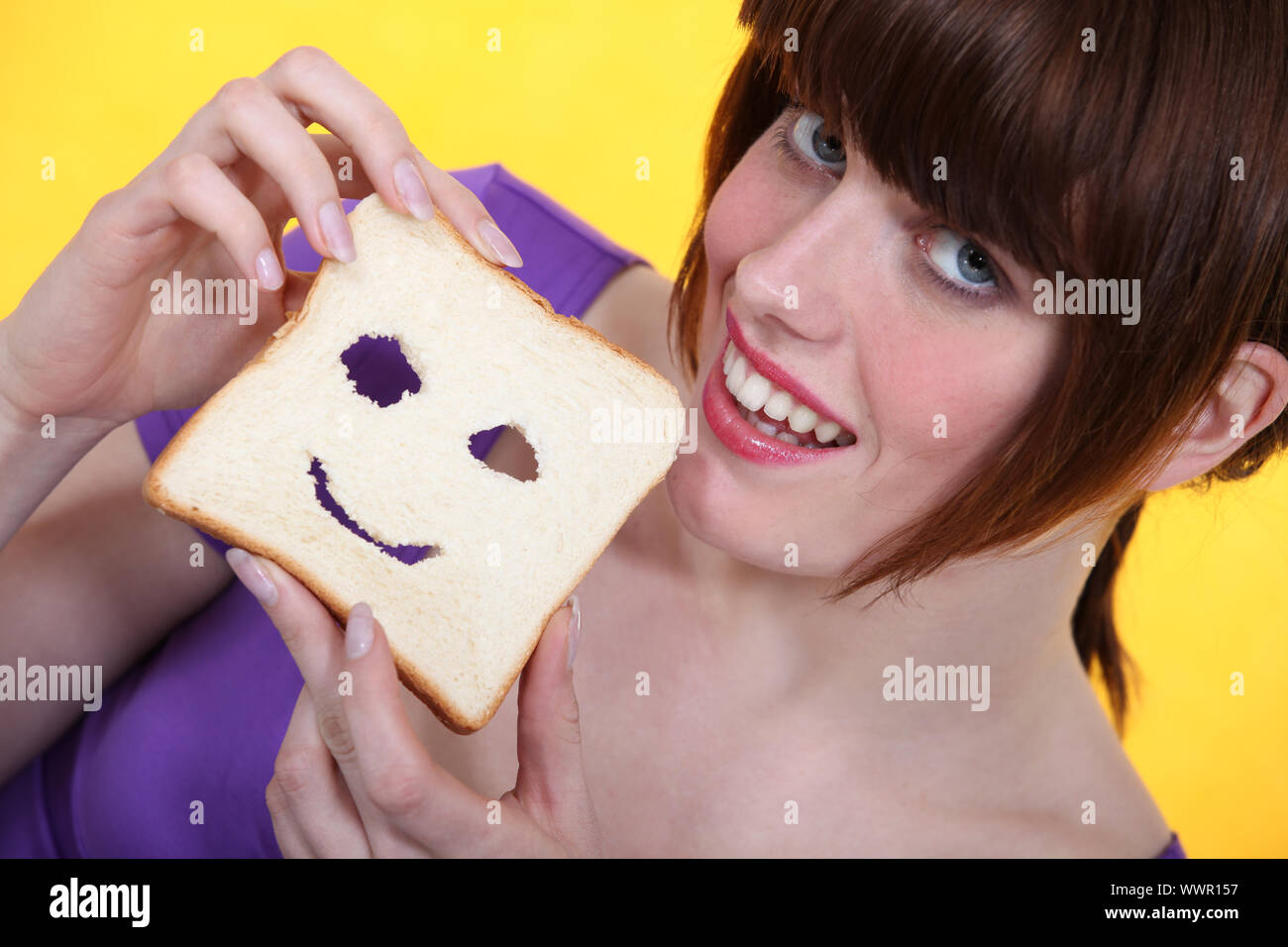Young woman making a face in her slice of bread Stock Photo - Alamy